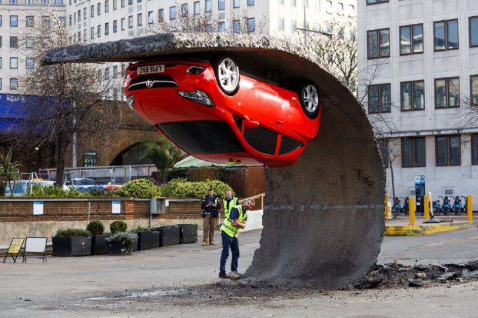 A parked car hangs 15 feet in the air while still attached to the road ...