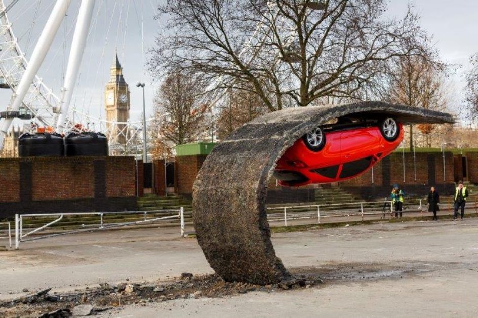 A parked car hangs 15 feet in the air while still attached to the road ...